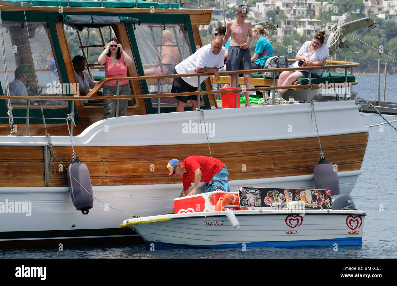 Ice cream salesman selling ices to holidaymakers onboard a boat in the ...
