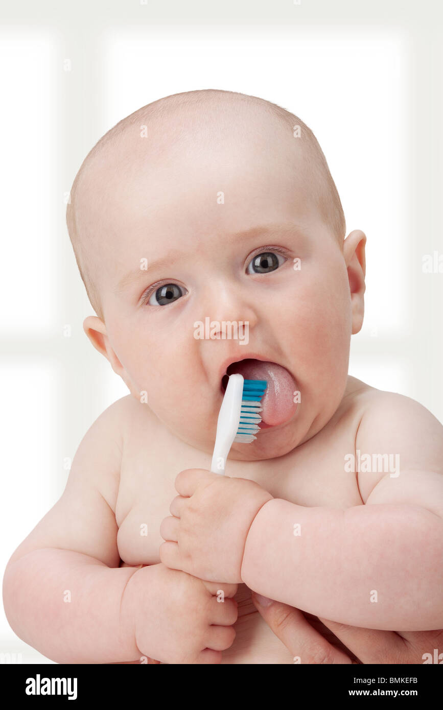 Baby boy playing with a new toothbrush Stock Photo - Alamy