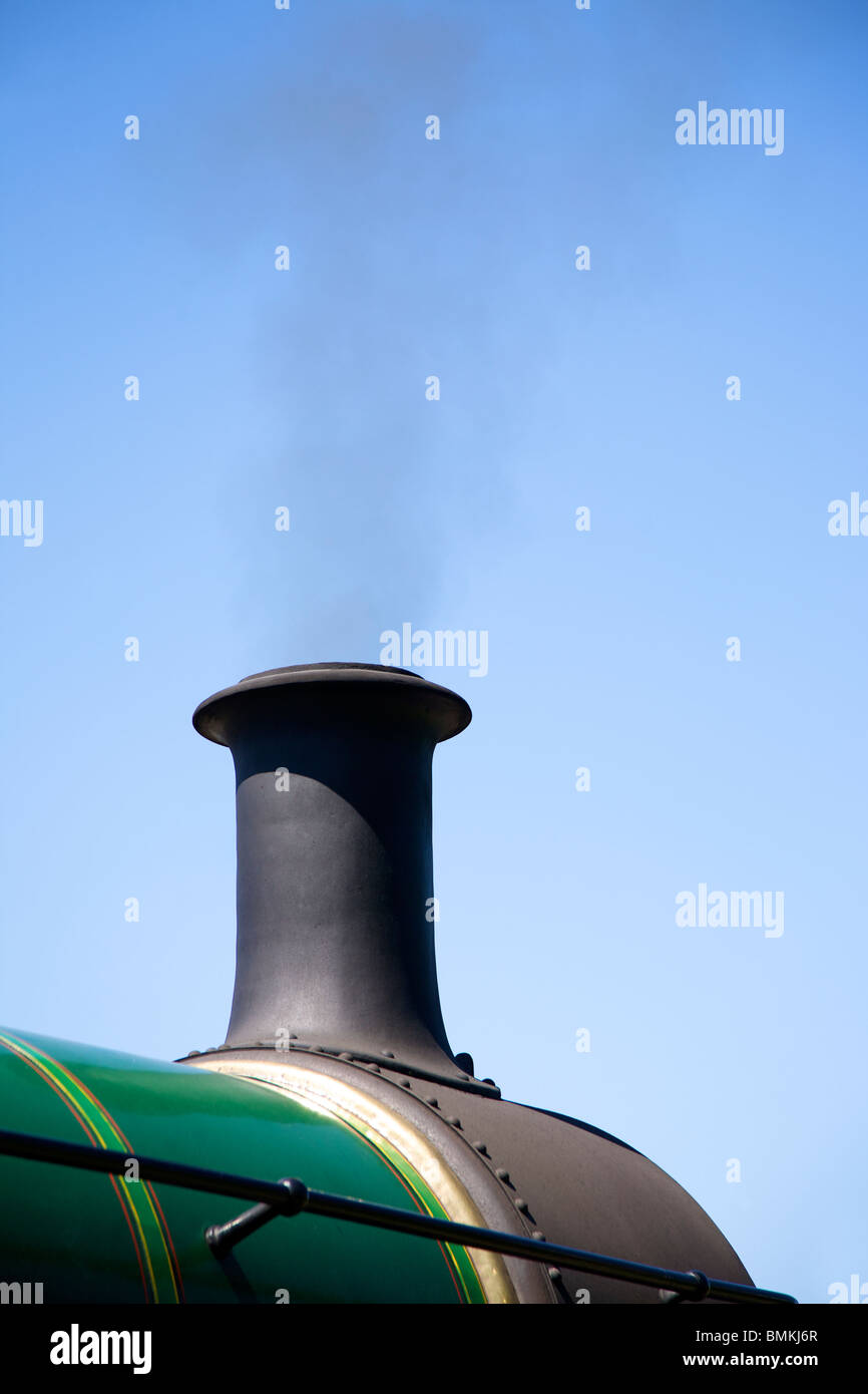 Chimney pot of a green railway steam engine emitting smoke and ...