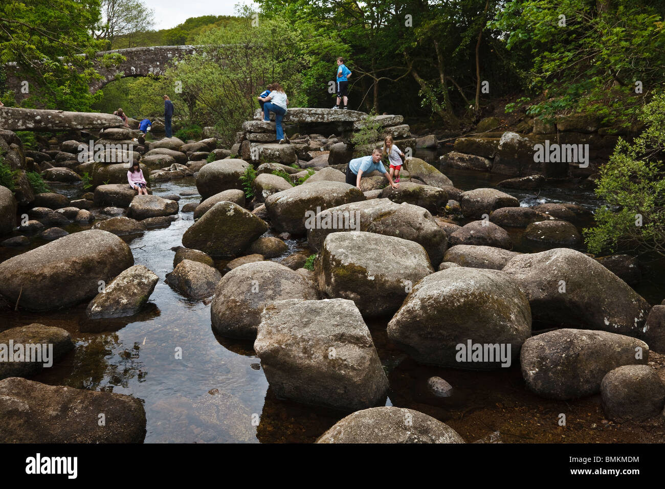 Children clambering over boulders in the East Dart River at Dartmeet ...