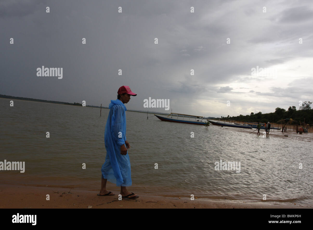 A man wearing protection against the rain at the Western Baray, a ...