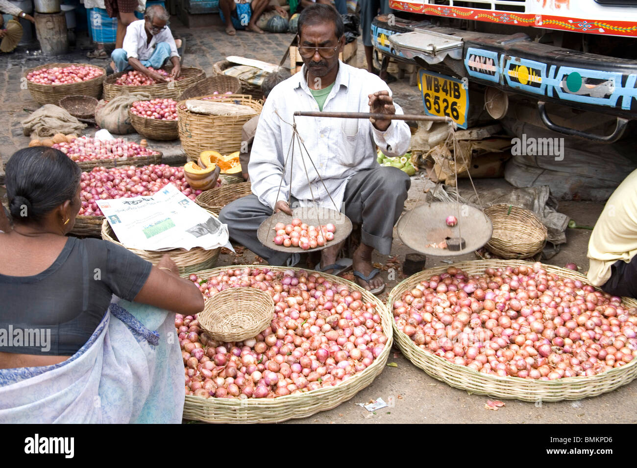Man measuring onions in weight scale selling to woman in vegetable ...