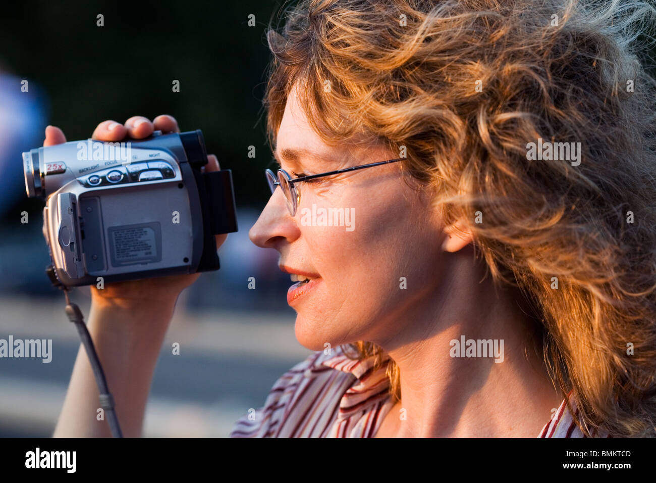 A young smiling woman recording, digital movie camera in hand, Rome ...
