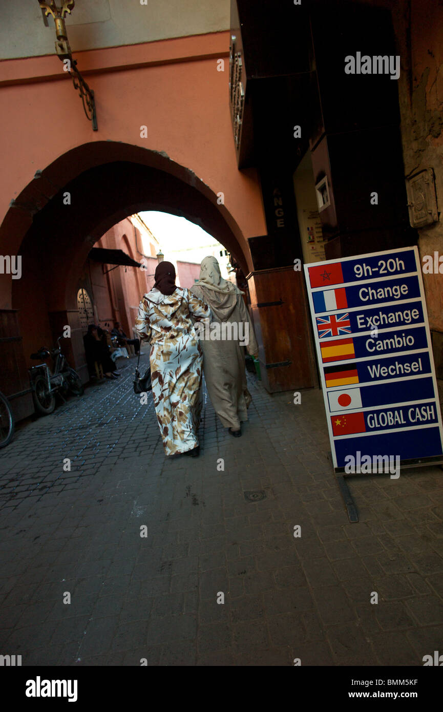 Two women in traditional dress pass a change sign Stock Photo - Alamy