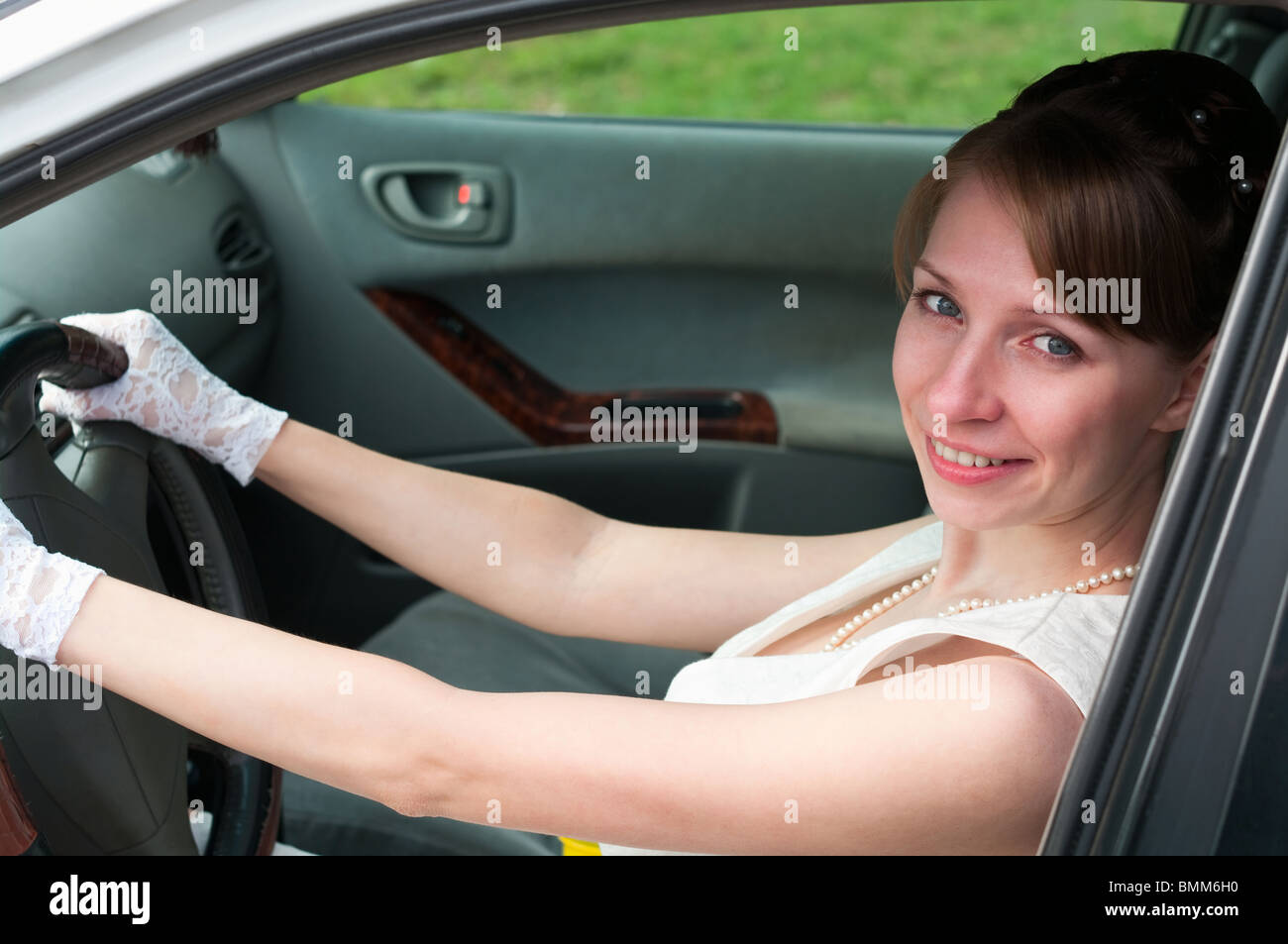 Woman in white dress and white-gloved sitting in car as a driver ...