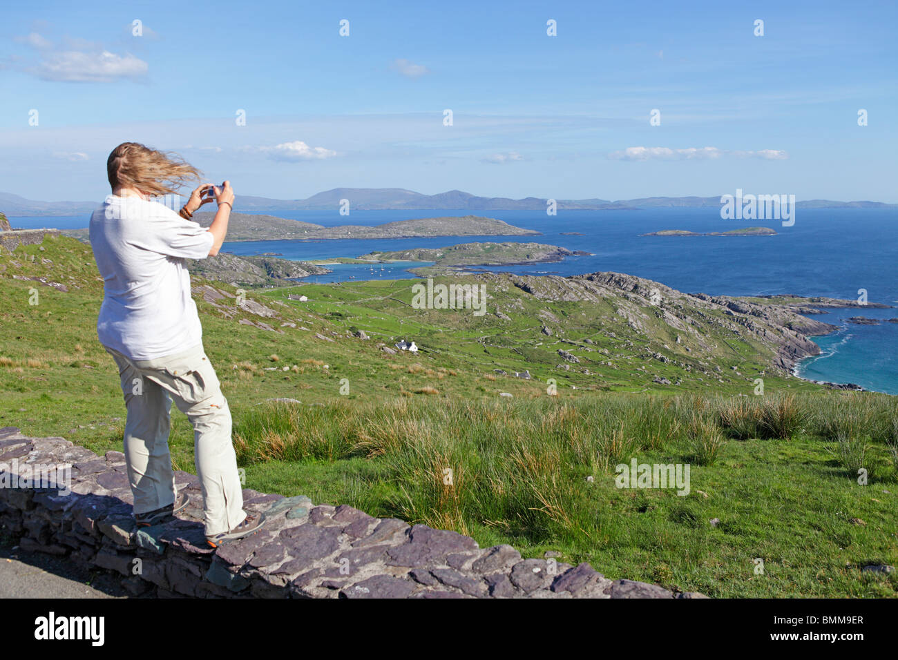 a woman taking photographs of the panoramic view of Ballinskelligs Bay ...