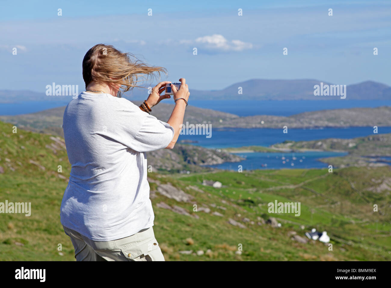 a woman taking photographs of the panoramic view of Ballinskelligs Bay ...