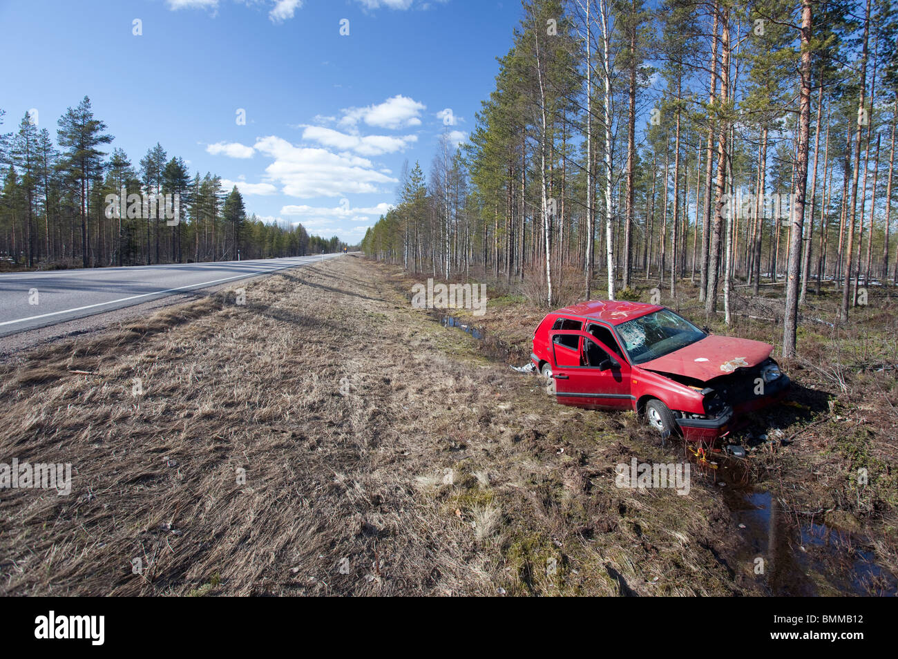 Crashed red VW Volkswagen Golf laying at roadside ditch at country road ...