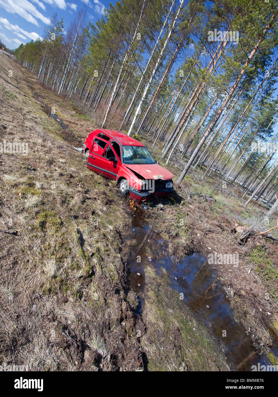 Crashed red VW Volkswagen Golf laying at roadside ditch at country road ...