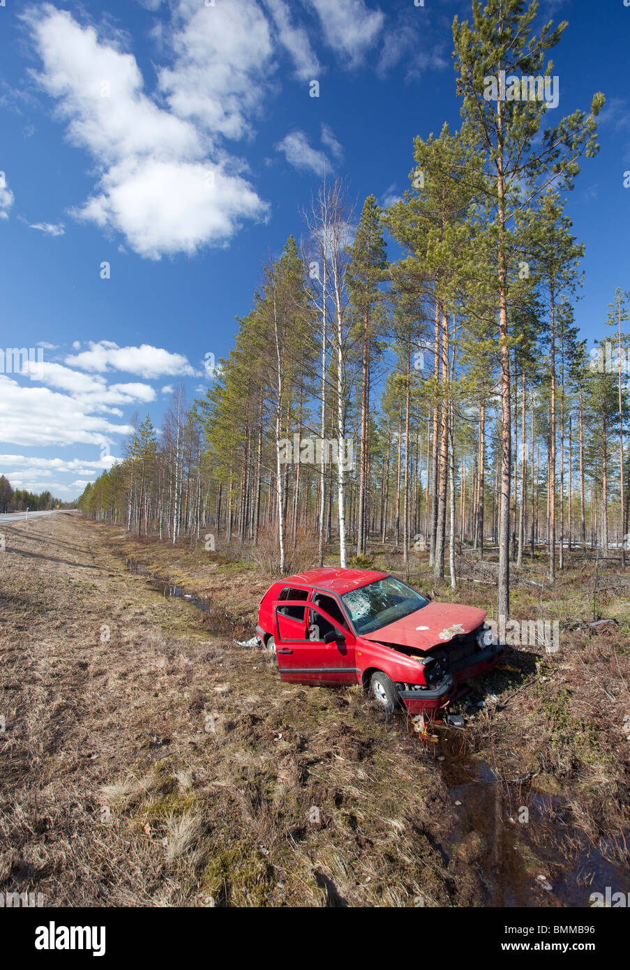 Crashed red VW Volkswagen Golf laying at roadside ditch at country road ...