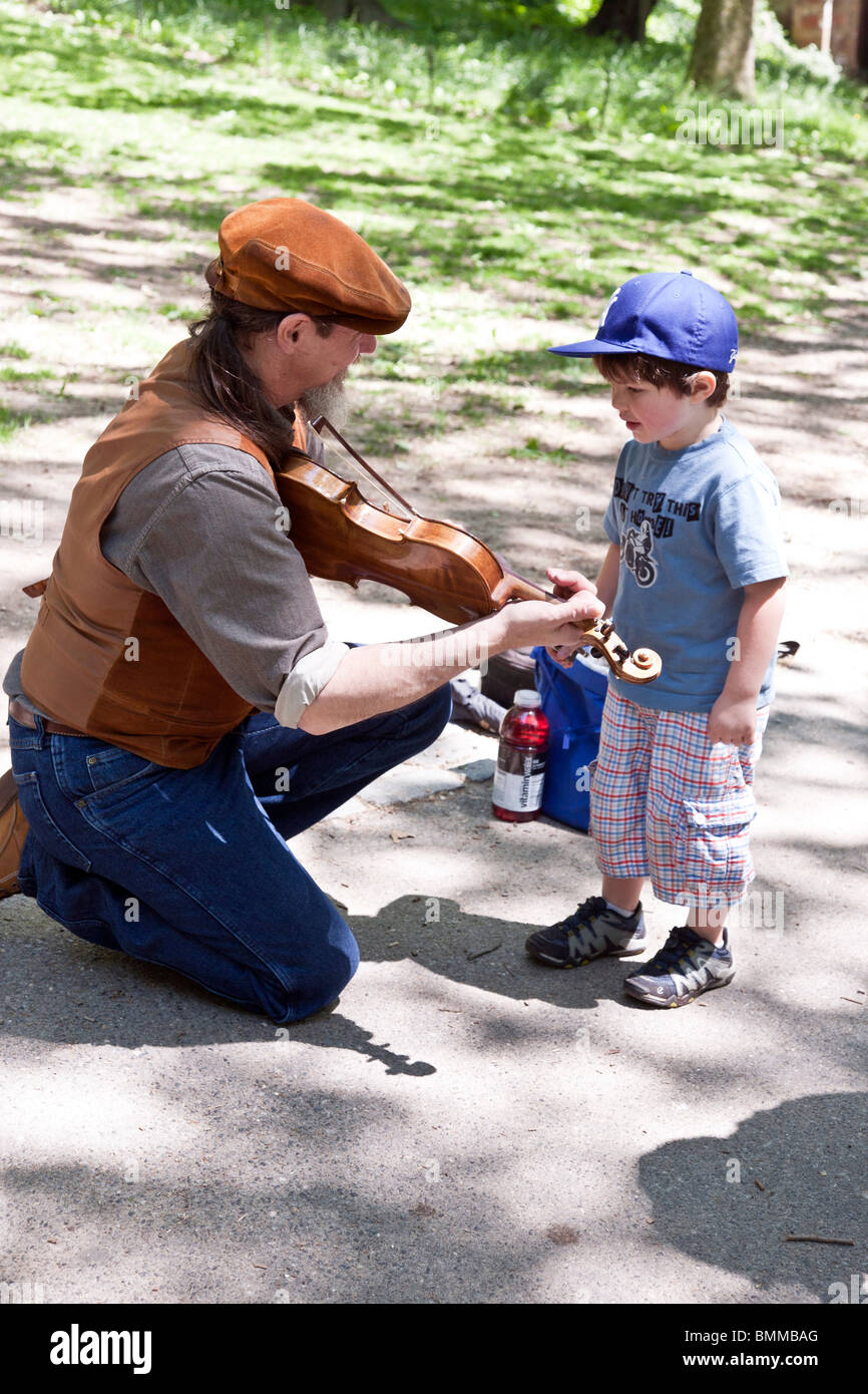 kindly Central Park fiddler kneels to demonstrate his instrument to ...