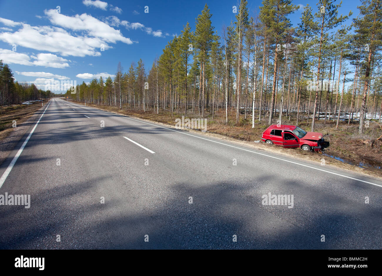 Crashed red VW Volkswagen Golf lying at roadside ditch at country road ...