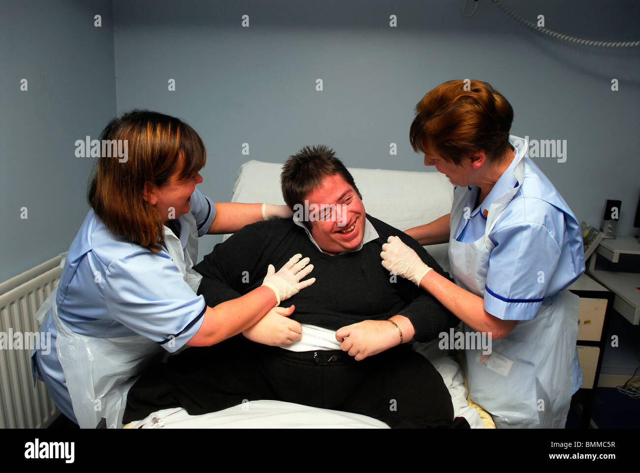 Care staff assisting disabled man with getting up in the morning ...