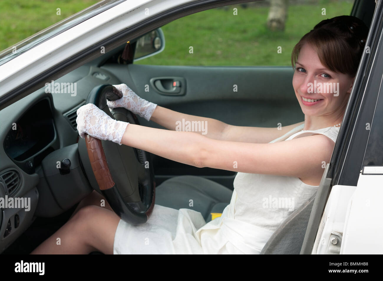 Woman in white dress and white-gloved sitting in car as a driver ...
