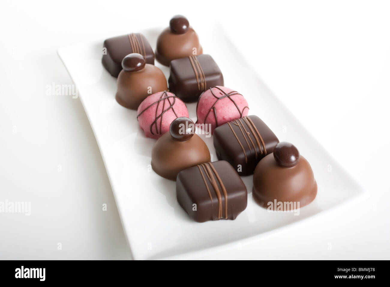 Variety of gourmet chocolates on long glass platter with white ...
