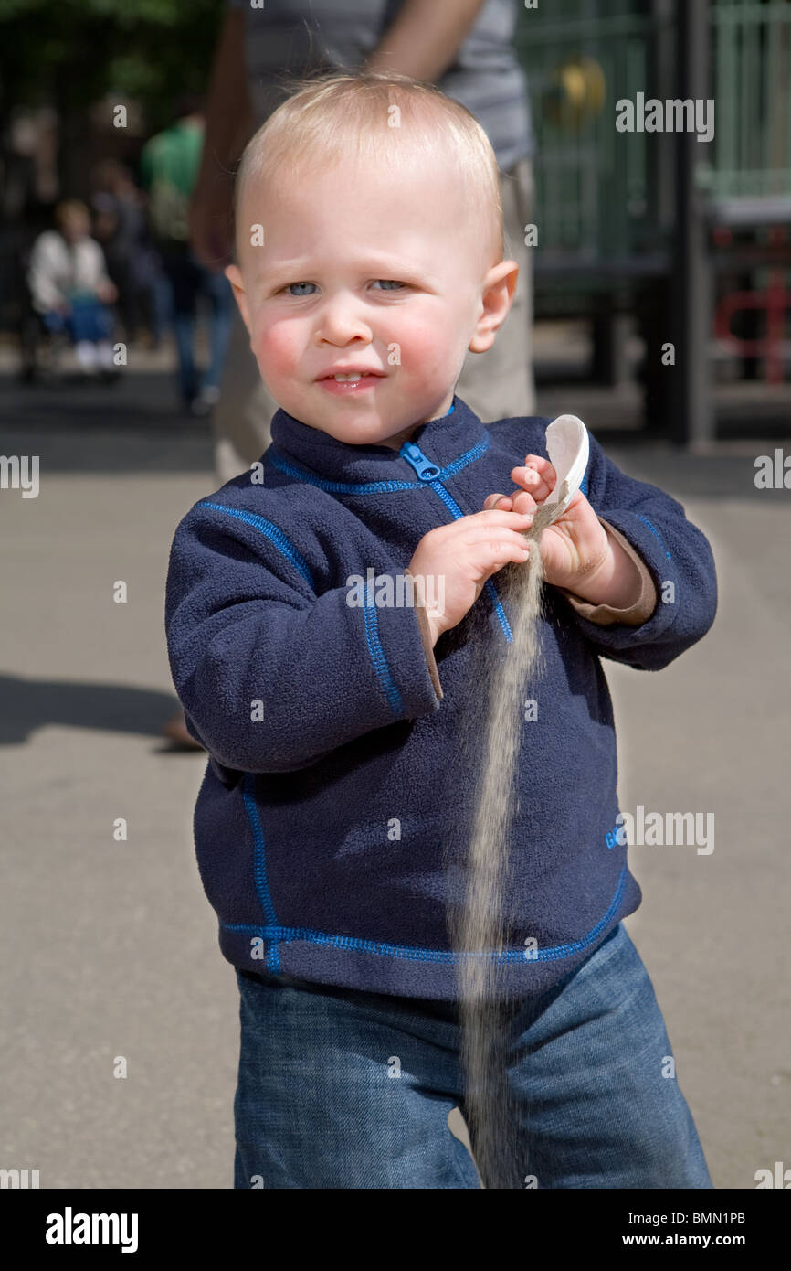 Young Boy with Shell Spilling Sand Stock Photo - Alamy