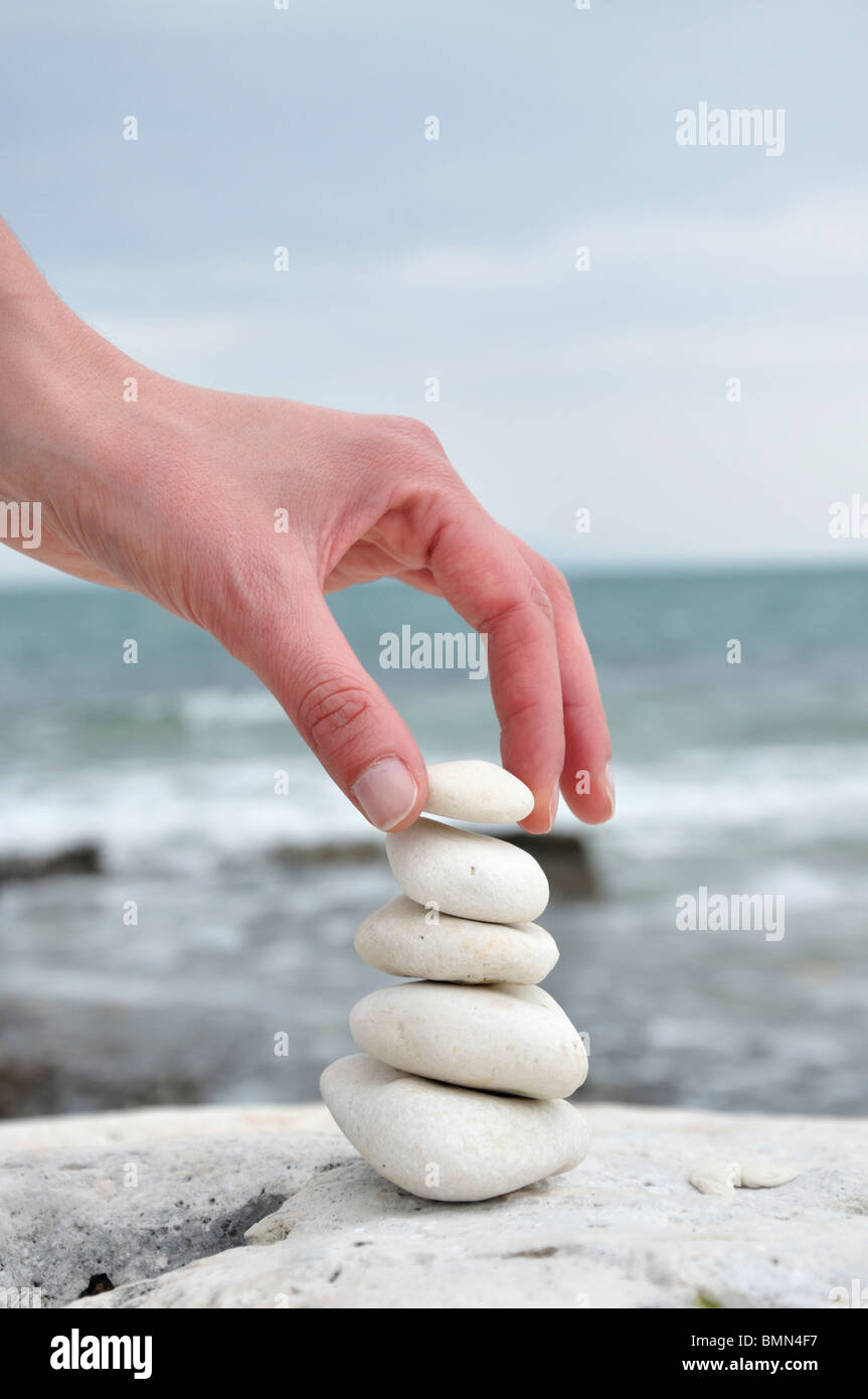 Woman stacking stones on beach close-up Stock Photo - Alamy