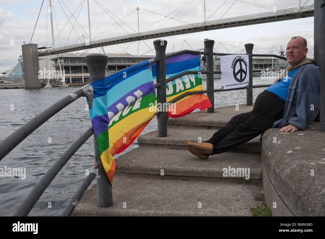 Peace protester with flags and peace symbol across the dock from Excel ...