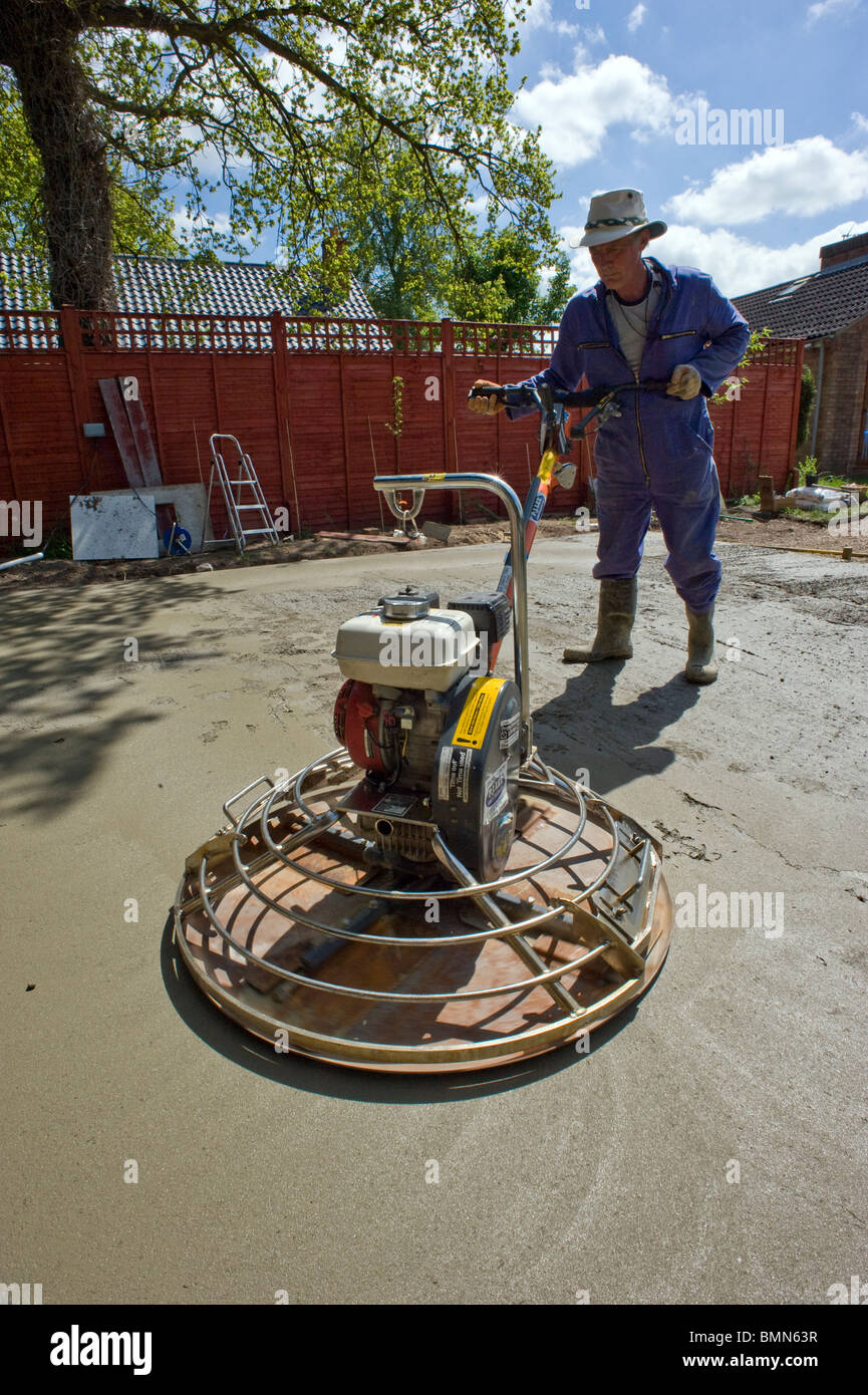 man levelling concrete base with power float Stock Photo - Alamy