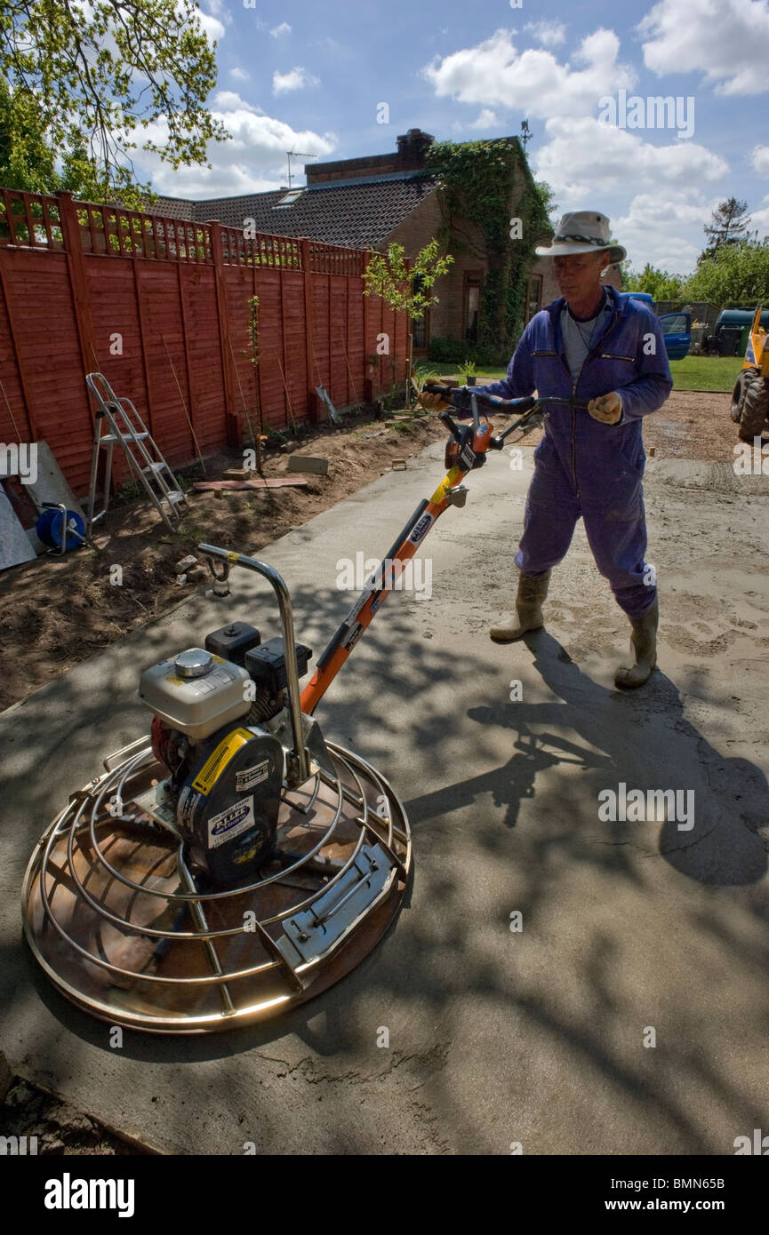 man levelling concrete base with power float Stock Photo - Alamy