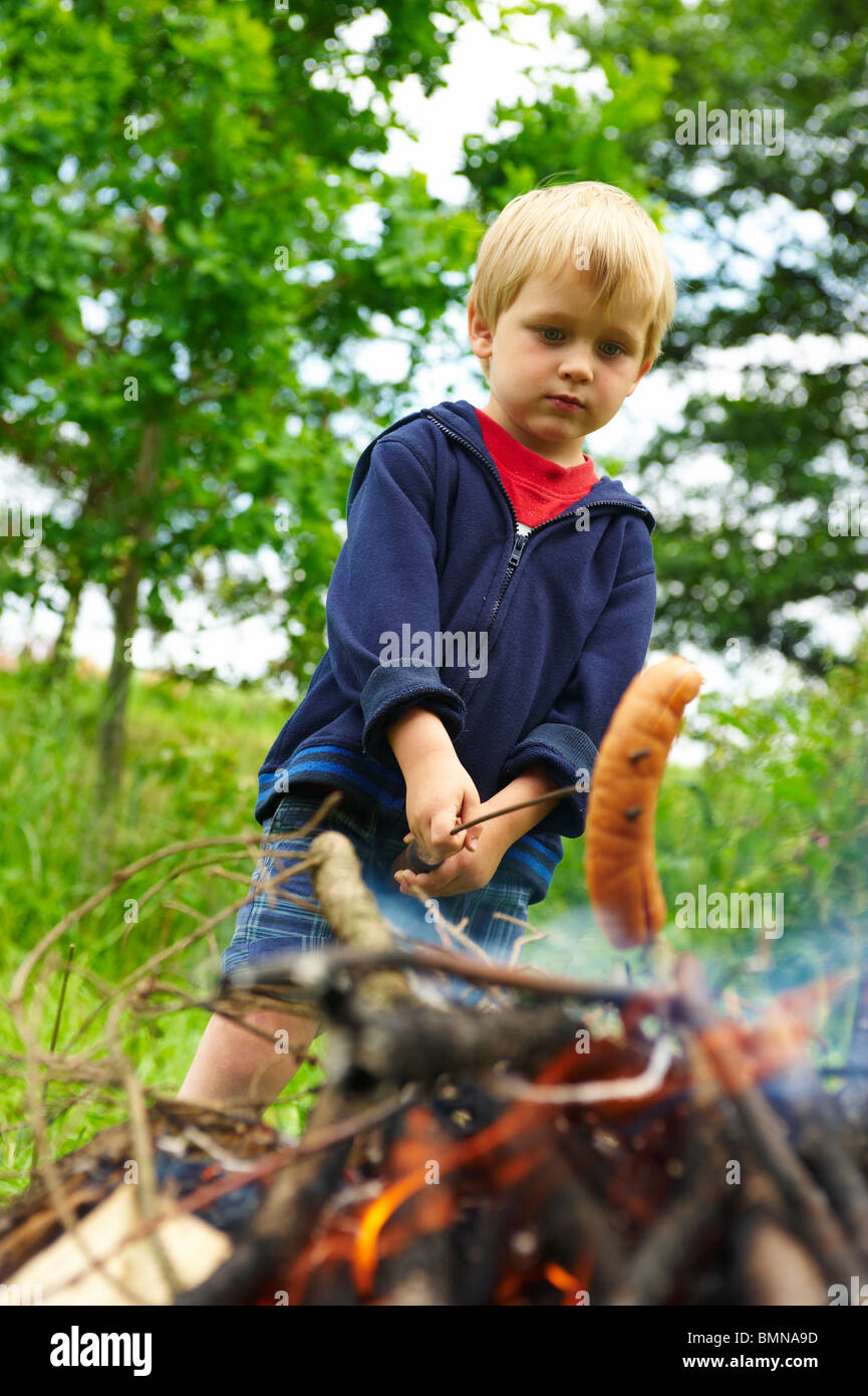 Child blond boy roasting sausage Stock Photo - Alamy