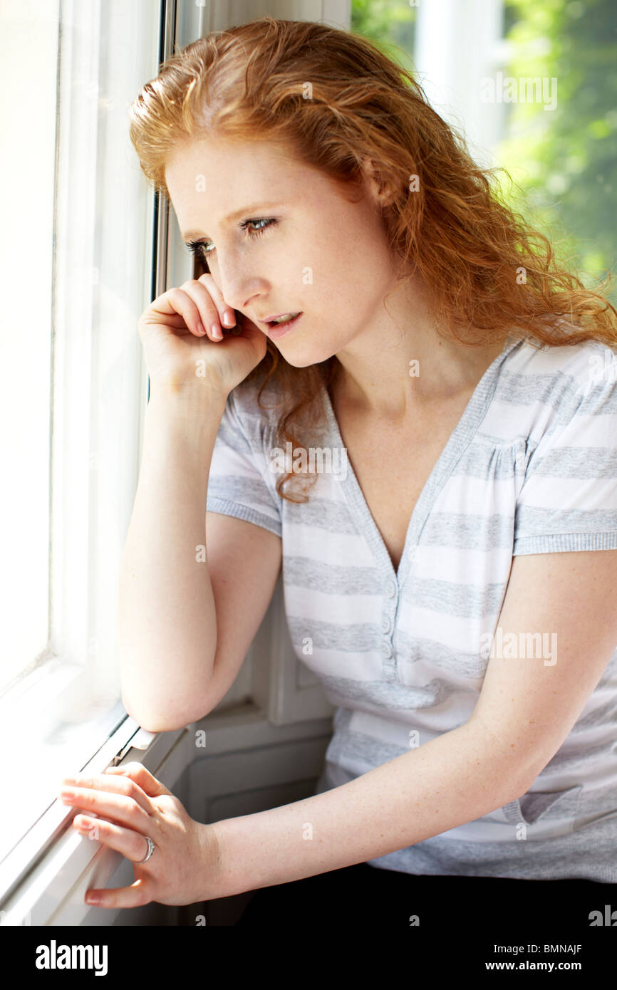 Woman looking sad out of window Stock Photo - Alamy