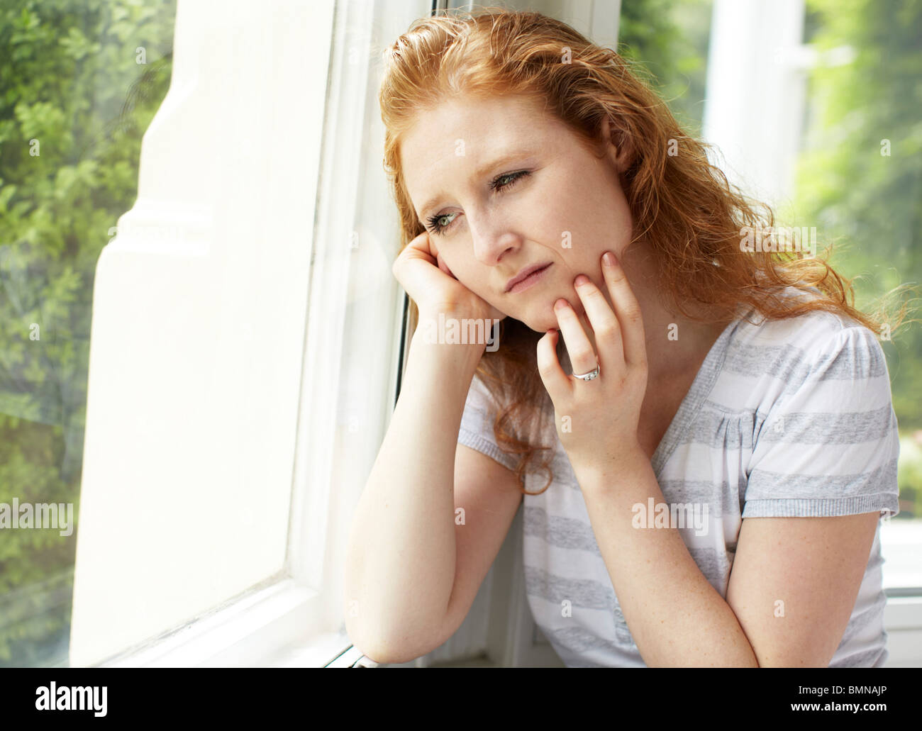 Woman looking sad out of window Stock Photo - Alamy