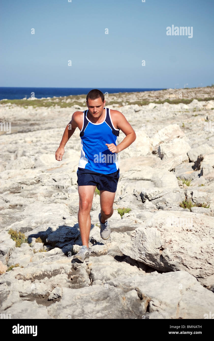 Man running along rocky beach Stock Photo - Alamy
