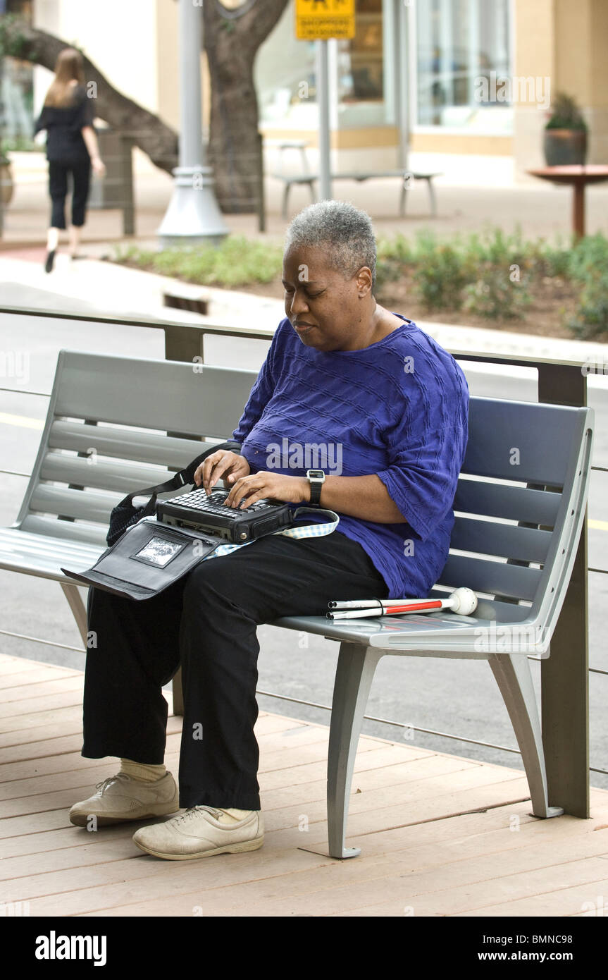 Female African-American types on her BrailleNote machine, similar to a ...