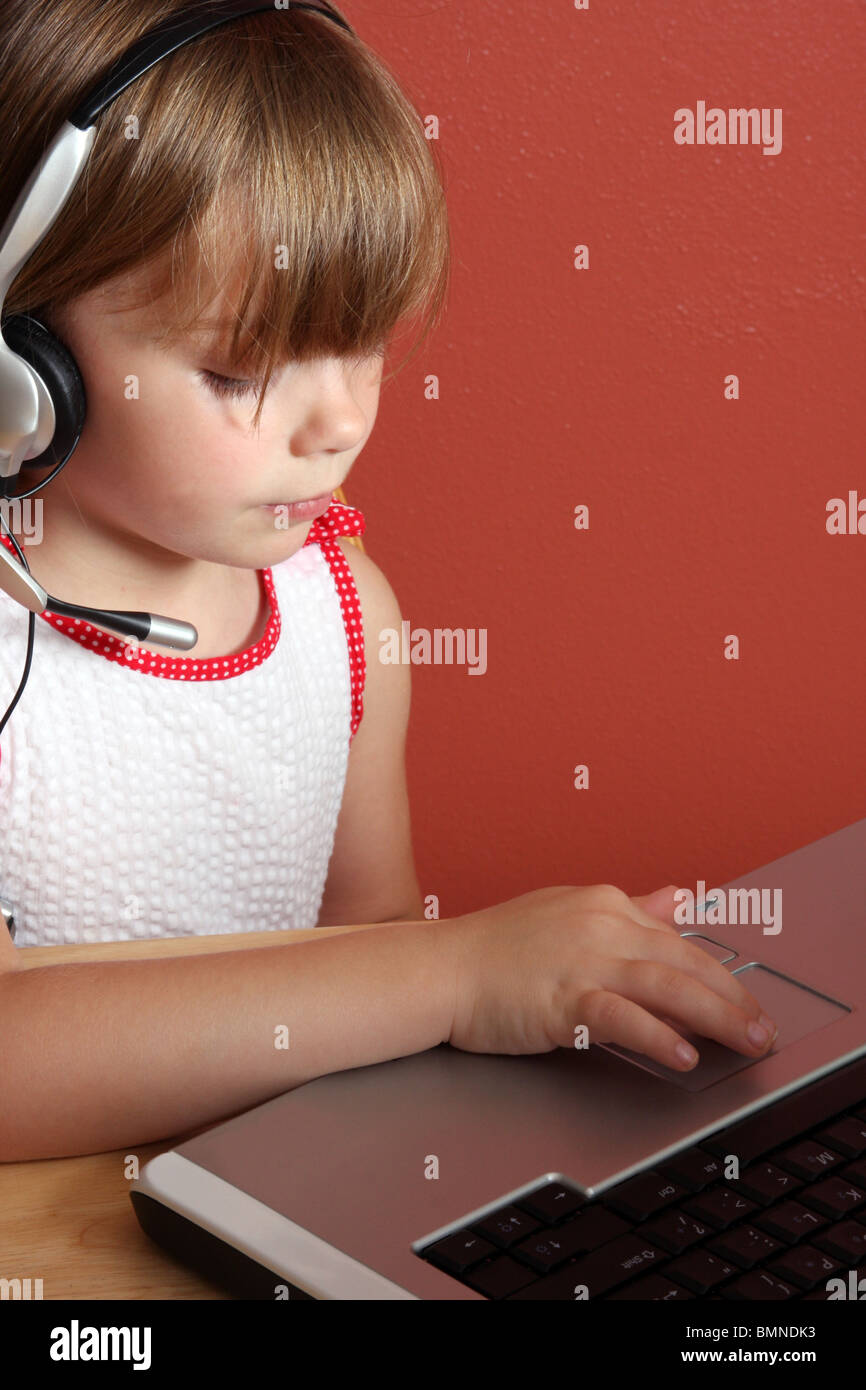 A young girl talking on a headset and working on a laptop business ...