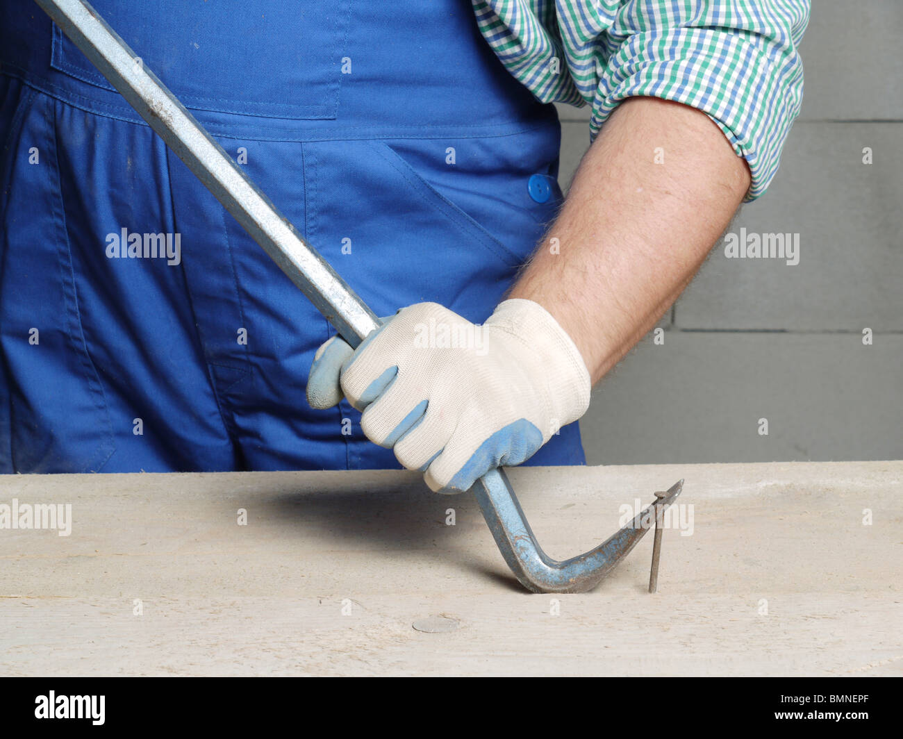 Worker pulling a nail from a plank using wrecking bar Stock Photo - Alamy