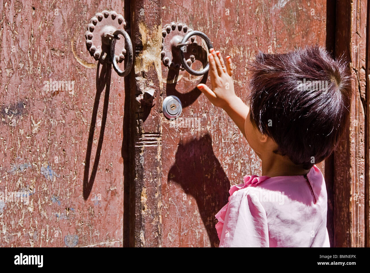 Child knocking on an iron door knocker of a big wooden door in China ...