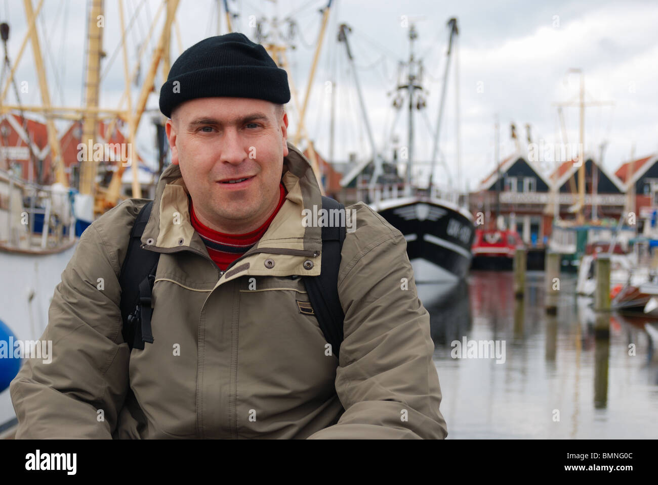 Man sitting at the Urk town pier with the boats at background Stock ...