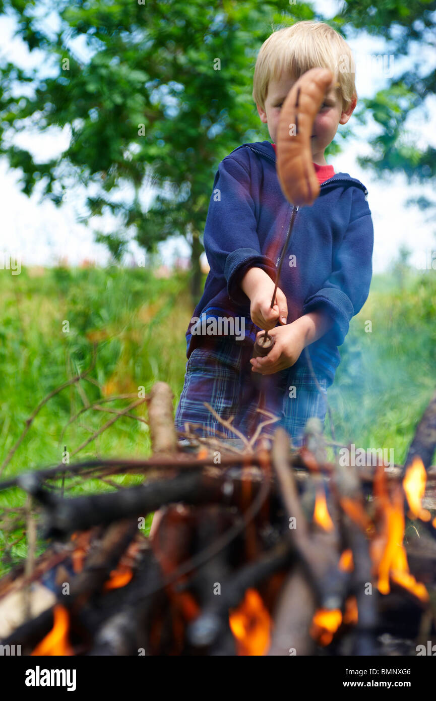 Child blond boy roasting sausage Stock Photo - Alamy