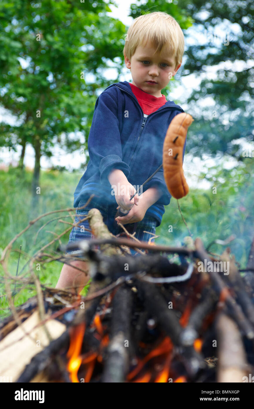 Child blond boy roasting sausage Stock Photo - Alamy