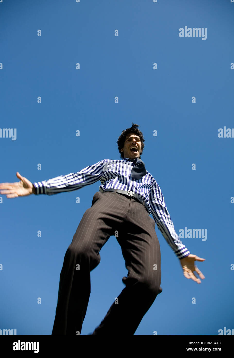 Young man in business/ formal dress jumping against blue sky Stock ...