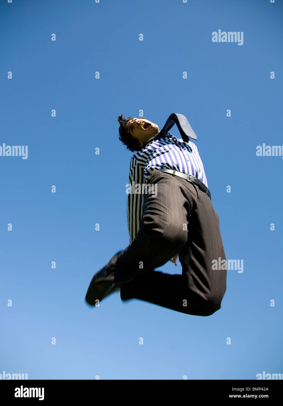 Young man in business/ formal dress jumping against blue sky Stock ...