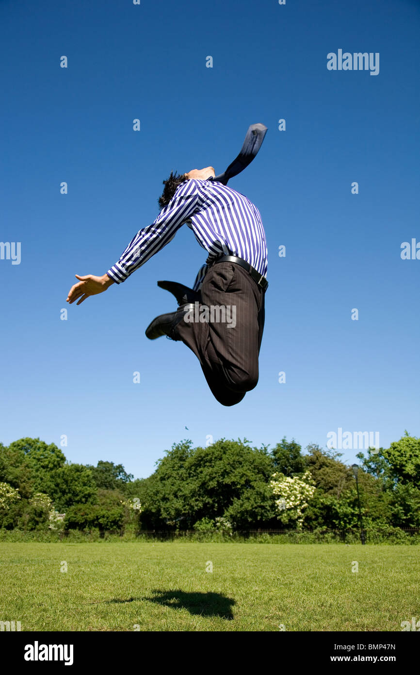 Man is business clothing jumping in the air in Park Stock Photo - Alamy