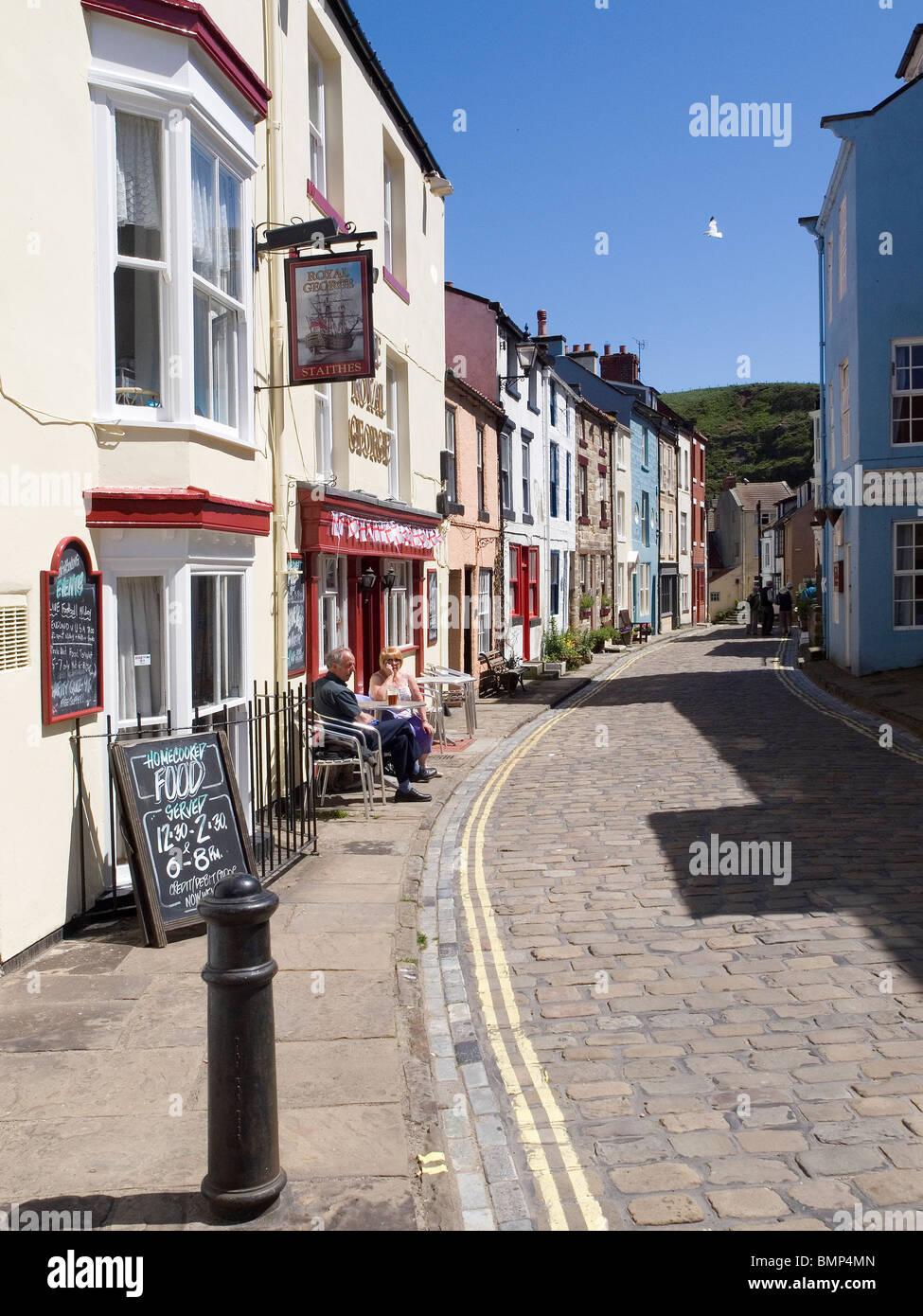 A couple sit the sun outside the Royal George pub in Staithes High ...