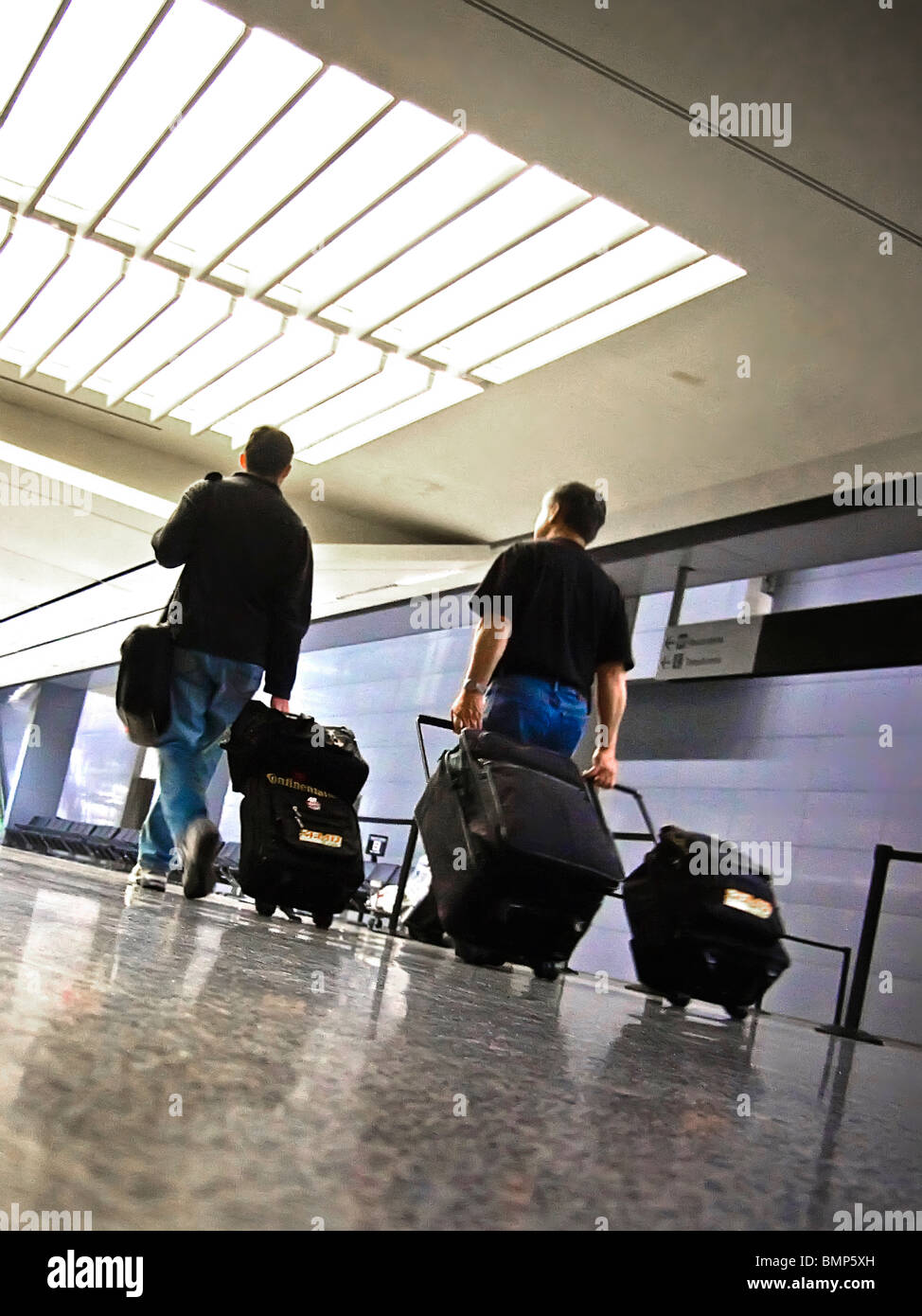 Two male passengers carrying and pulling their luggage through San ...