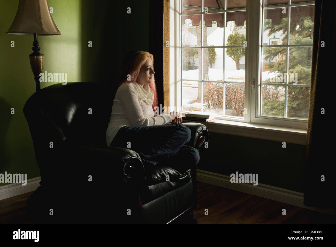 A Woman Sitting In A Large Chair Looking Out The Window Stock Photo - Alamy