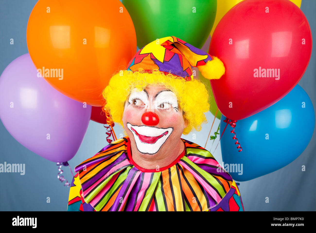 Adorable friendly birthday clown surrounded by colorful balloons Stock ...