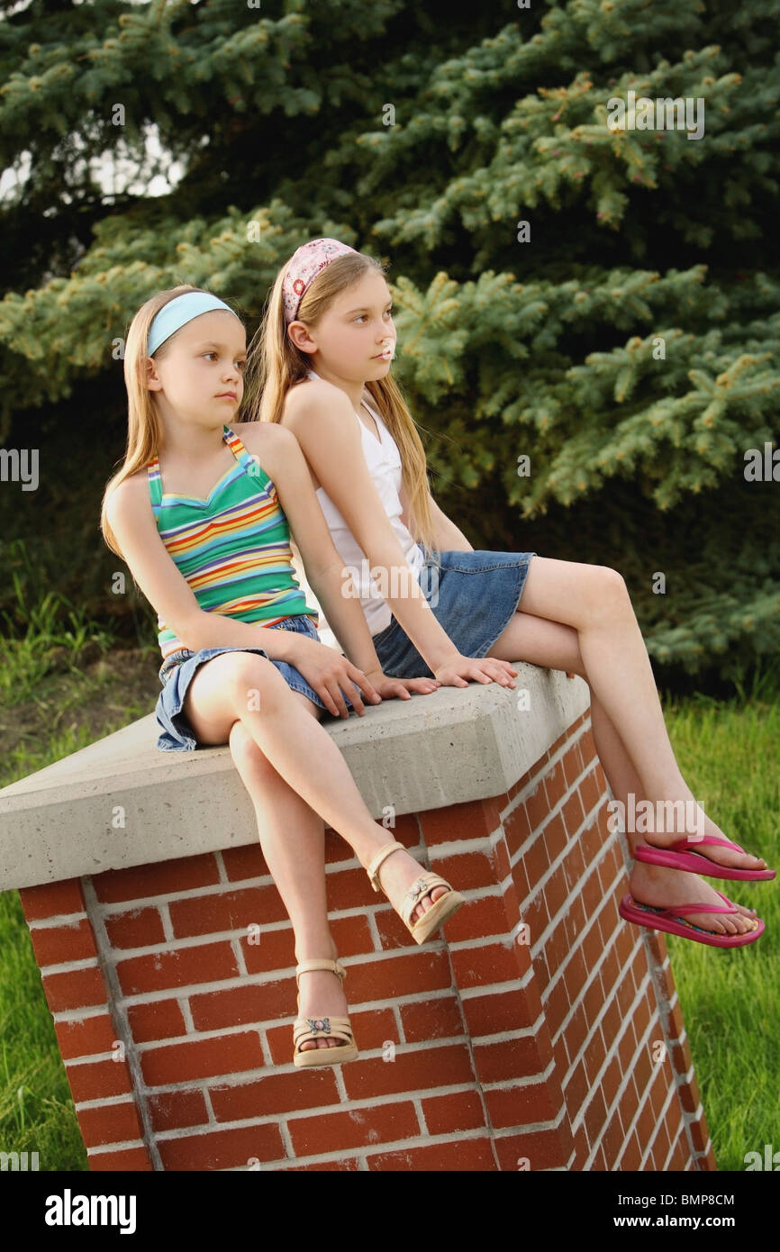 Edmonton, Alberta, Canada; Two Girls Sitting On A Brick Pillar Stock ...
