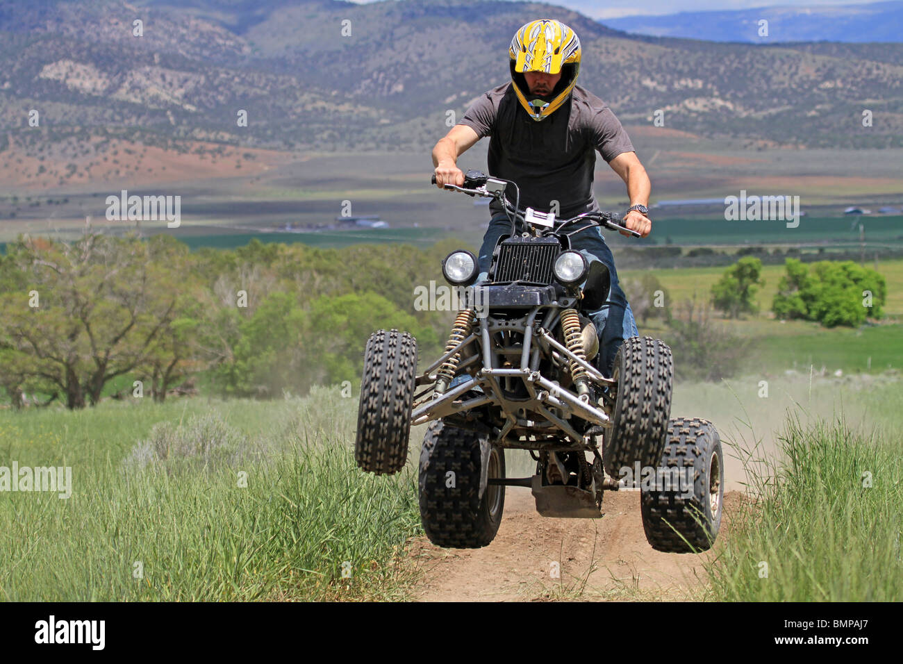 Motorcycle ATV ride on rough dirt track by man.Jumps over earth ramps ...