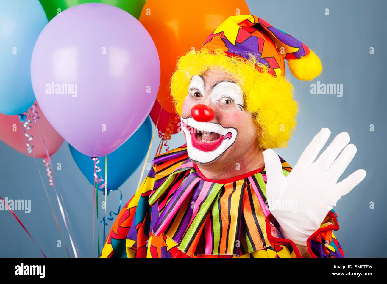 Happy clown with helium balloons, waving hello Stock Photo - Alamy