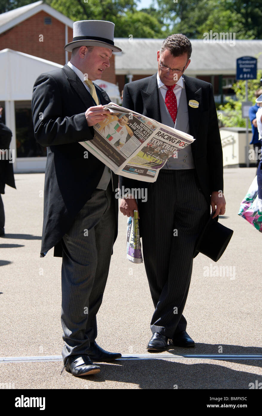 Two race goers in top hats reading the Racing Post newspaper to check ...
