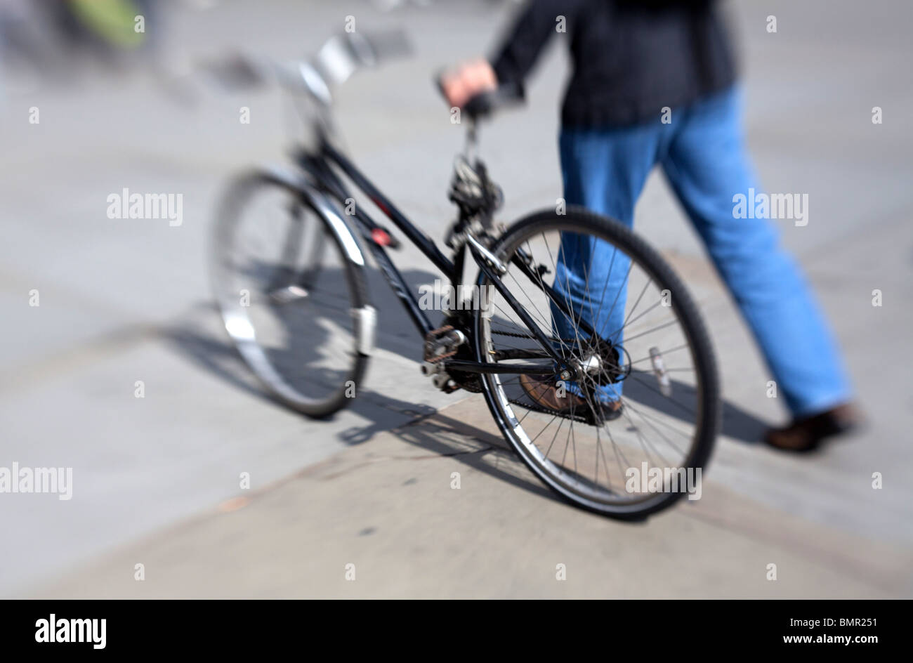 A man walking with his bicycle through Trafalgar Square in London ...