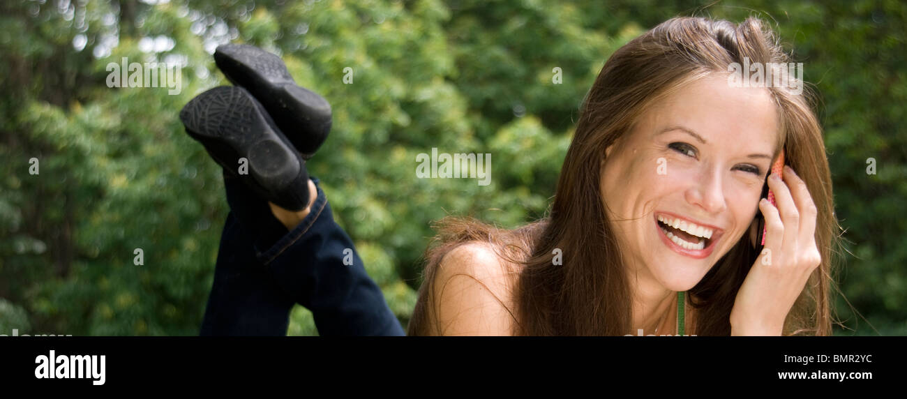 Attractive Brunette Female lays in the park talking on her cell phone ...