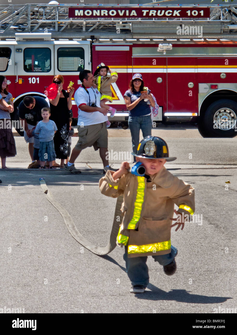 Wearing a junior-size firefighter's coat and helmet, a little boy ...