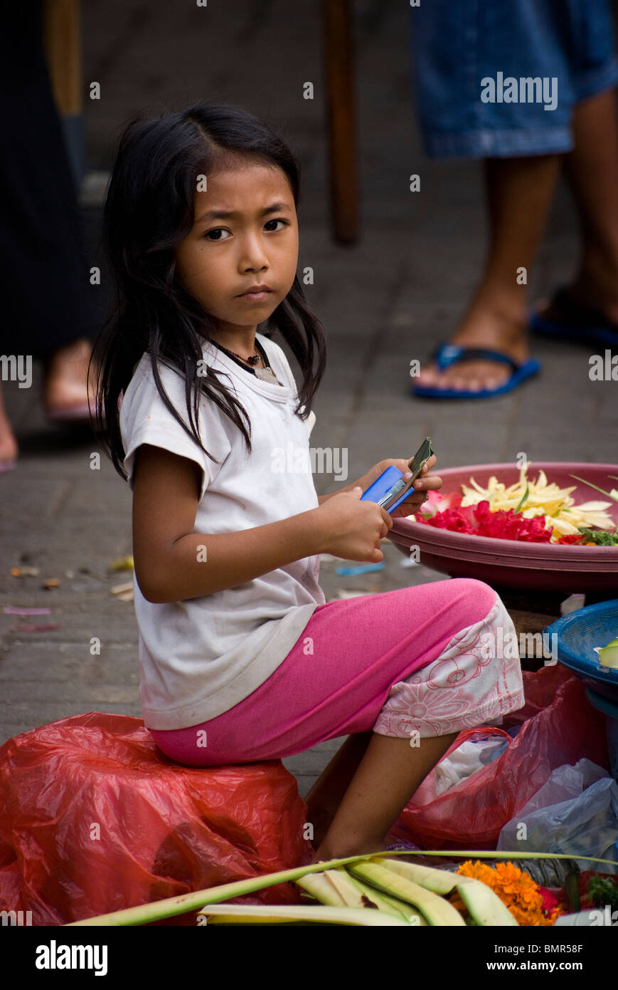 A girl at the Ubud, Bali public market makes Hindu offerings from palm ...